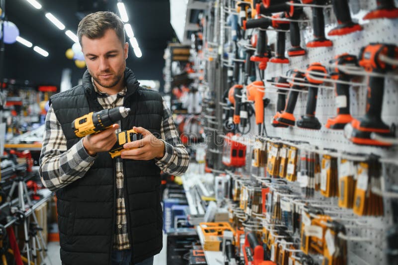 Man Holding and Choosing Electric Screwdriver, Standing in Construction ...