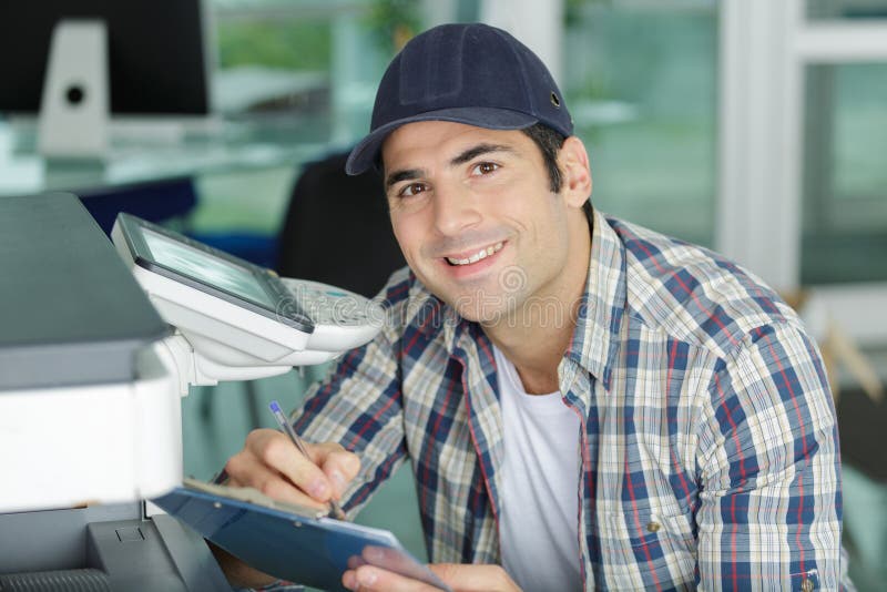 Man Holding Clipboard Next To Printer in Office Stock Image - Image of ...