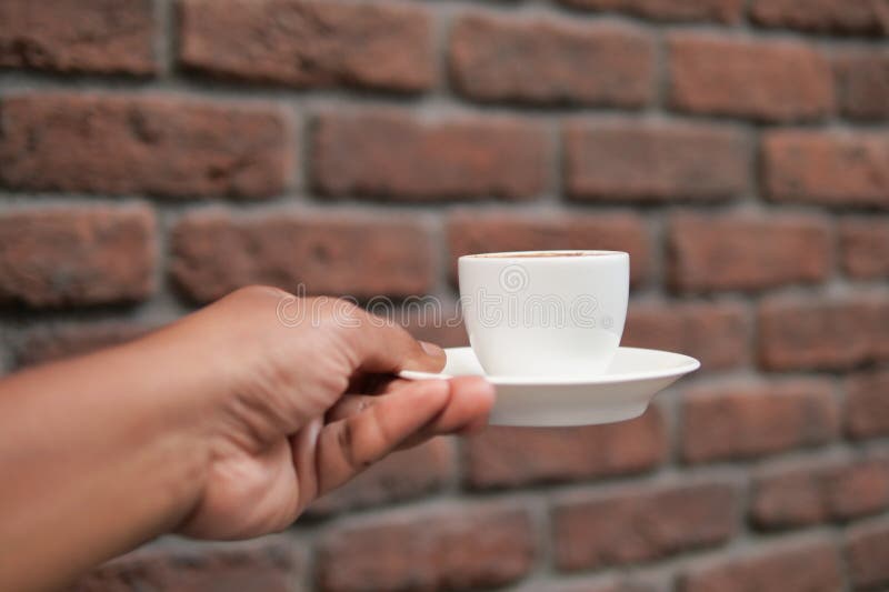 Man Holding a Coffee Cup Against Brick Wall Stock Photo - Image of ...