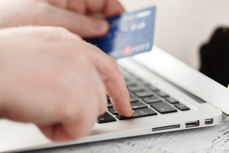 Man Holding Credit Card in Hand and Entering Security Code Using Laptop ...