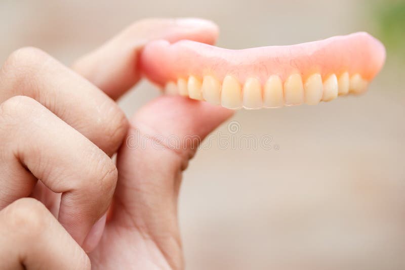 A Man is Holding Dentures in His Hands. Removable Dentures Flexible ...