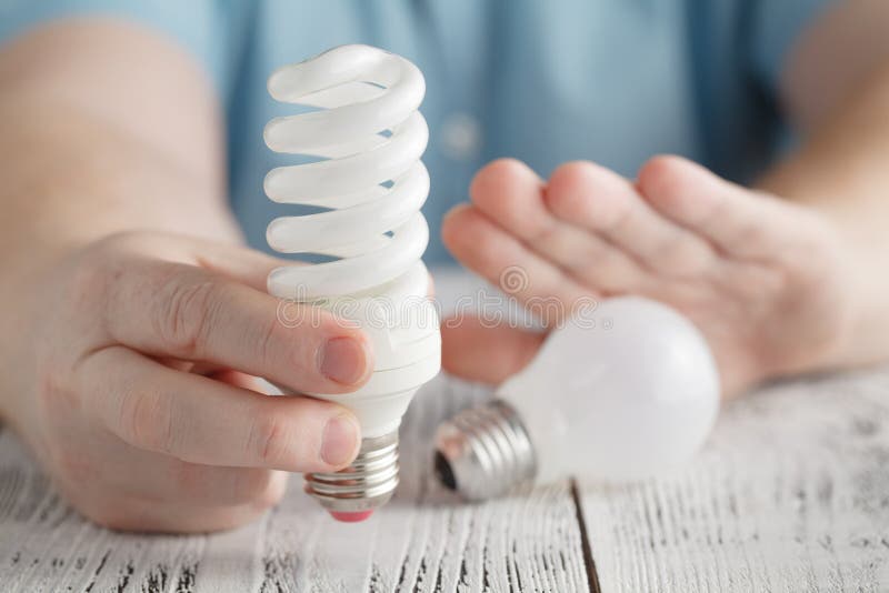 Man Holding an Energy Saving Lamp and Refuse Normal Light Bulb Stock ...