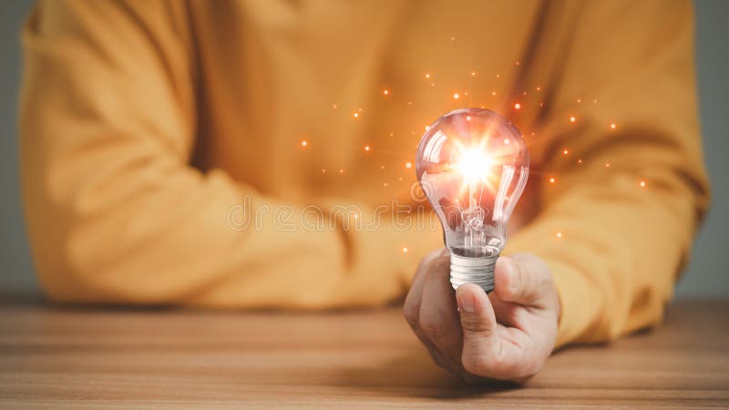 Man Holding a Glowing Abstract Light Bulb on a Wooden Table. Stock ...