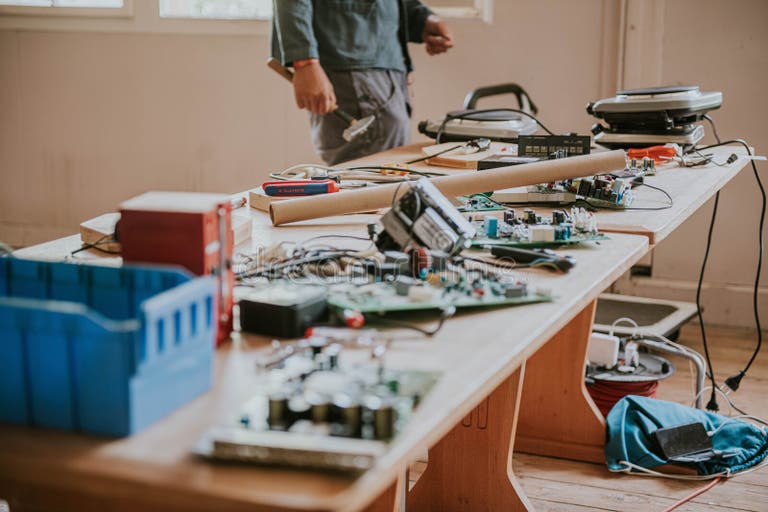 Man Holding a Hammer in Front of a Table with Electronic Parts on it ...