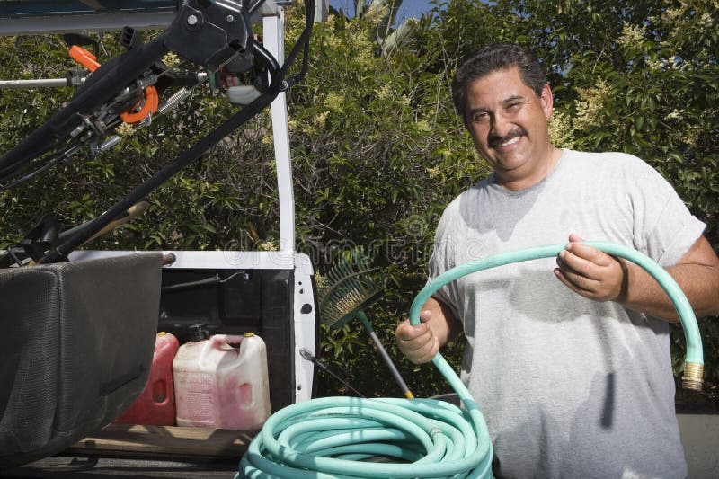 Man Holding Hose in Garden stock photo. Image of horizontal - 29664506