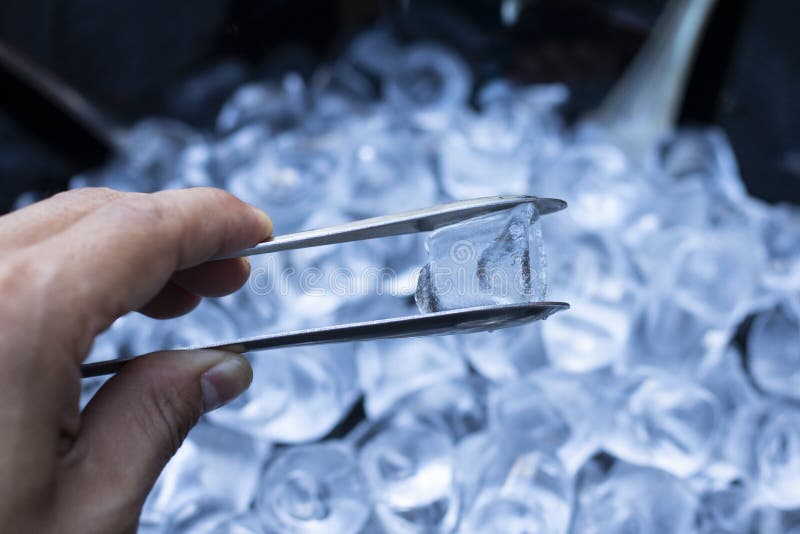 Man Holding the Ice Clip. Much Ice Cubes Background. Close Up Stock ...