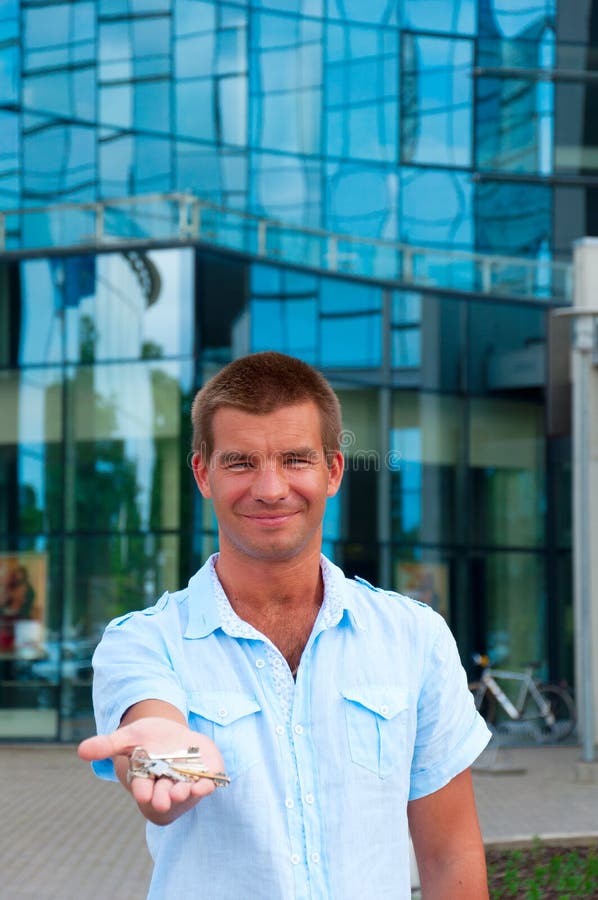 Man Holding a Key in Front of Modern Business Building Stock Photo ...