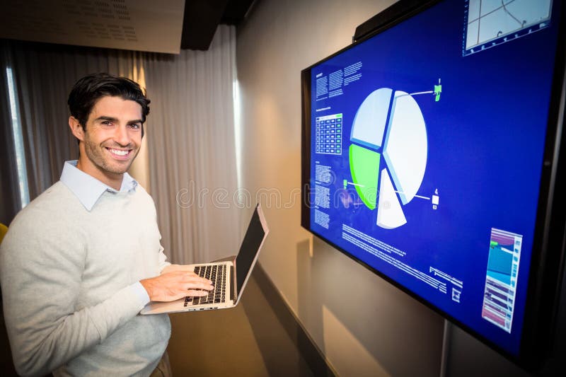 Man Holding Laptop and Presenting Pie Chart Data on Wall Display in ...