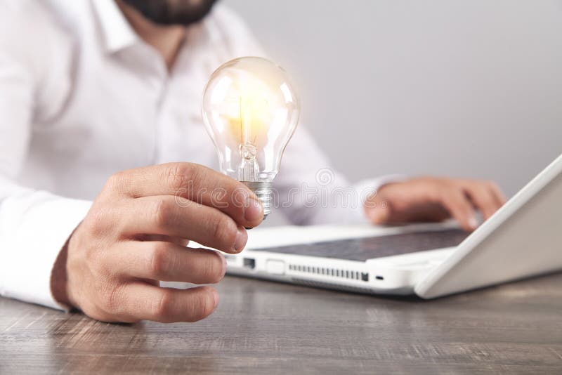 Man Holding Light Bulb and Using Laptop Computer Stock Image - Image of ...