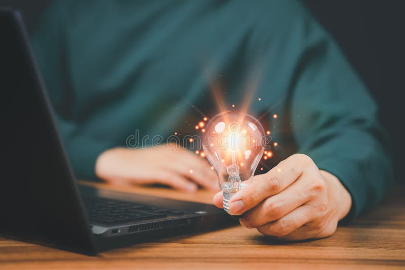 Man Holding a Light Bulb while Working on the Computer To Think and ...