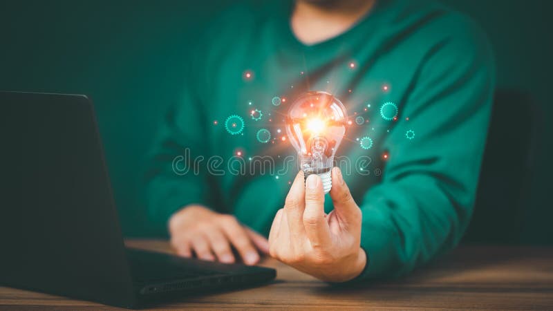 Man Holding a Light Bulb while Working on the Computer To Think and ...