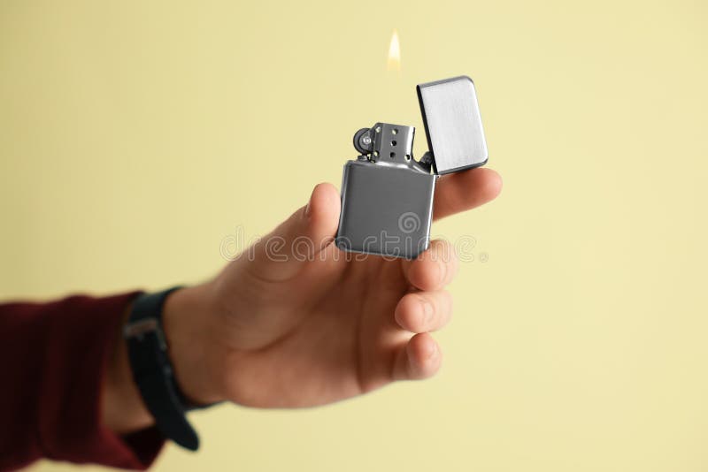 Man Holding Lighter with Burning Flame Against Beige Background ...