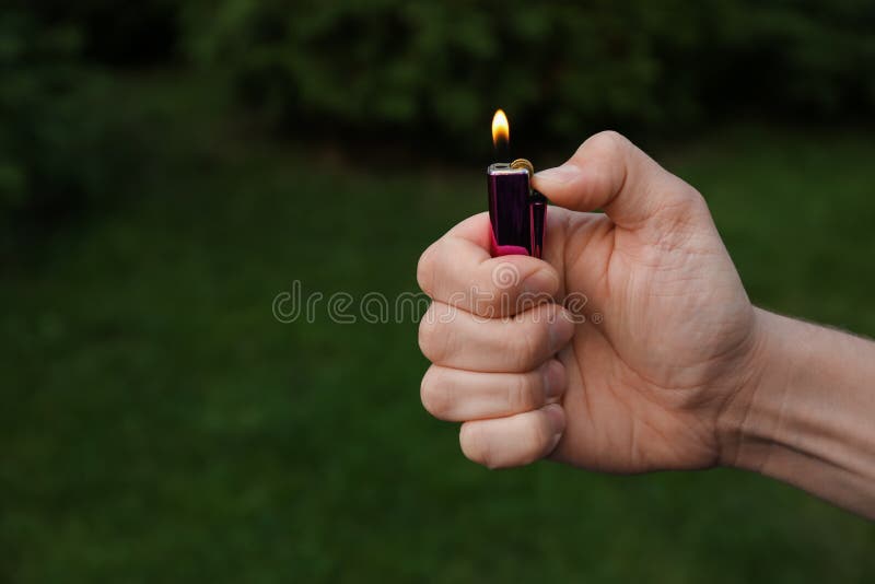 Man Holding Lighter with Burning Flame Outdoors, Closeup. Space for ...