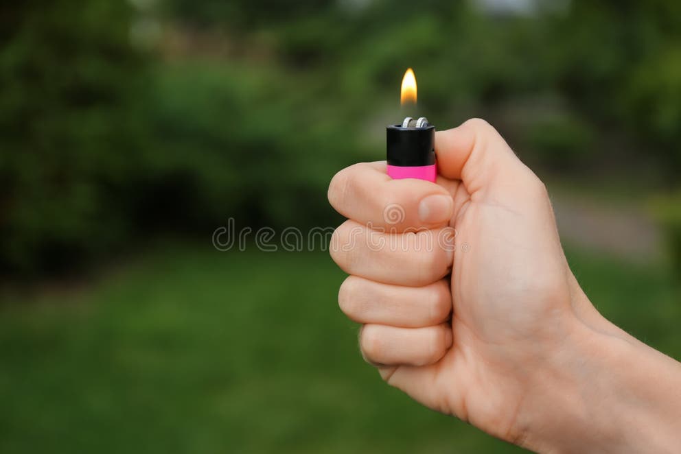 Man Holding Lighter with Burning Flame Outdoors, Closeup. Space for ...