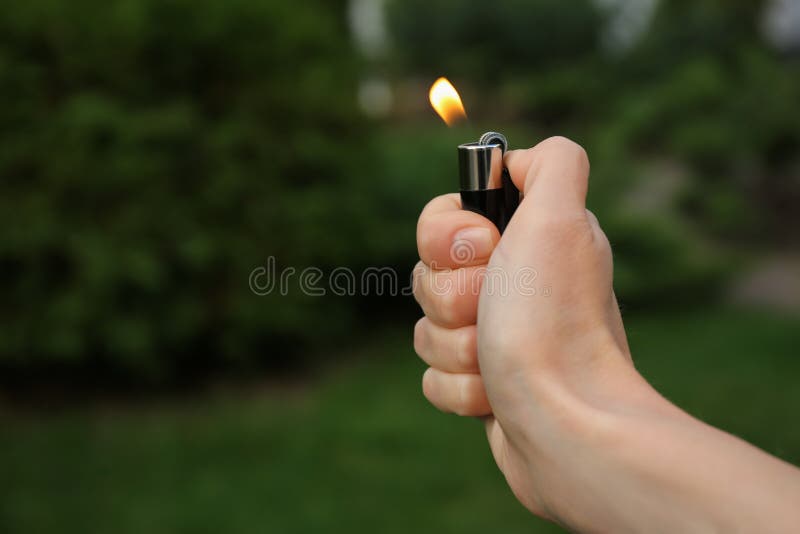 Man Holding Lighter with Burning Flame Outdoors, Closeup. Space for ...
