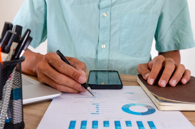 Man Holding a Pen and Analyzing a Graph of a Report at Workplace with ...