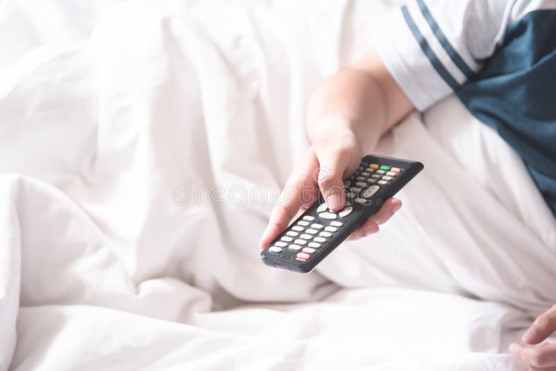 A Man Holding a Remote Control Stock Image - Image of bedroom, light ...