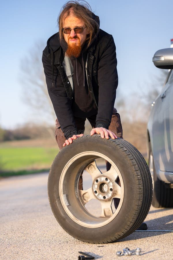 Man Holding Spare Tire at Roadside Pitstop Stock Photo - Image of ...