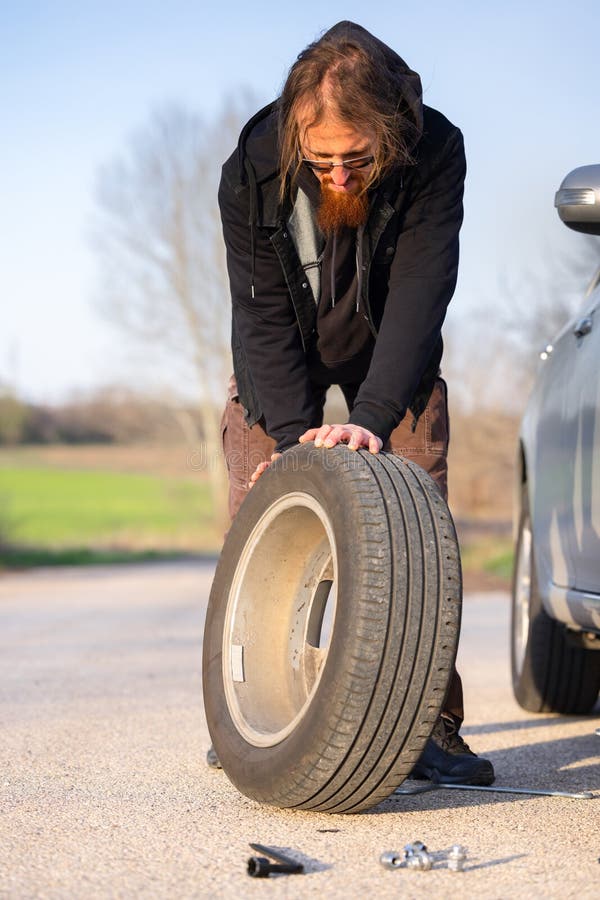 Man Holding Spare Tire at Roadside Pitstop Stock Image - Image of road ...