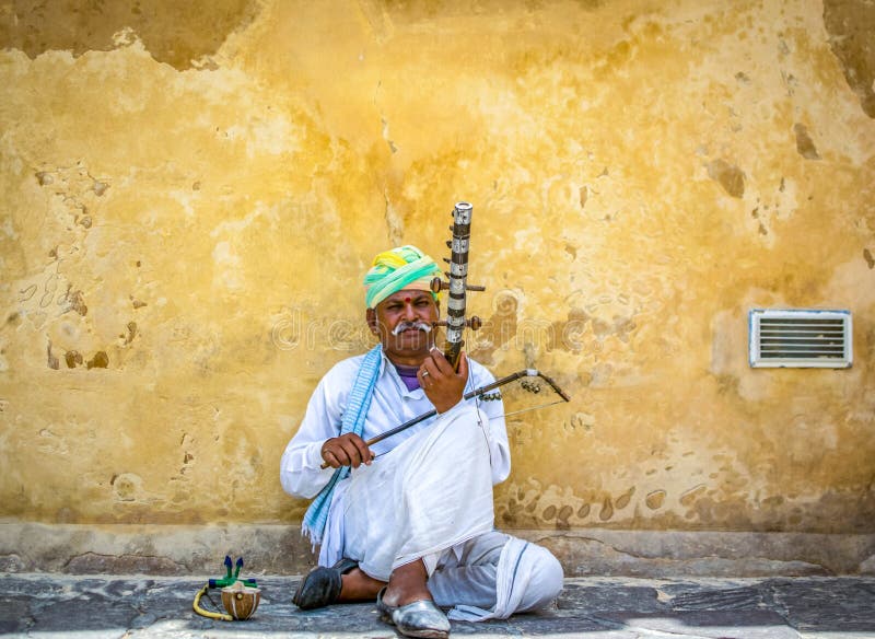 Man Holding String Instrument While Sitting On Concrete Pavement ...