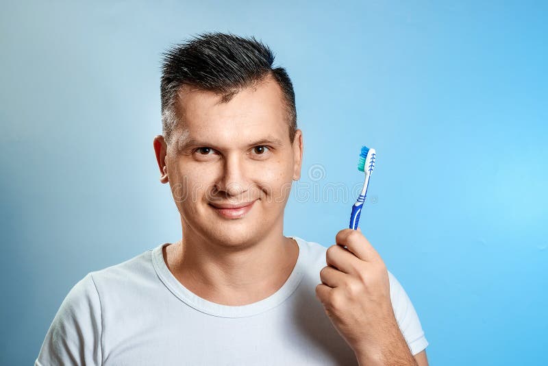 A Man is Holding a Toothbrush, Brushing His Teeth. the Concept of Oral ...