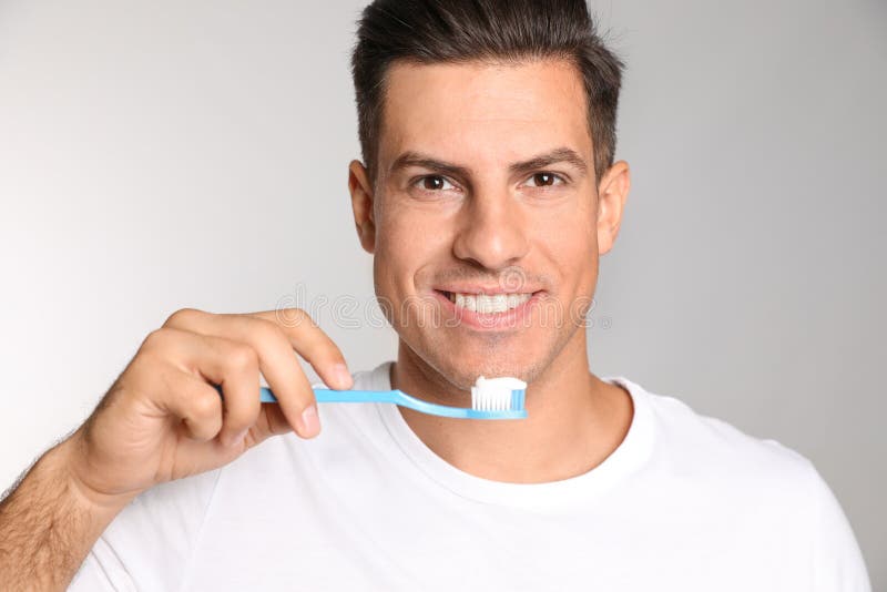 Man Holding Toothbrush with Paste on Light Background Stock Photo ...