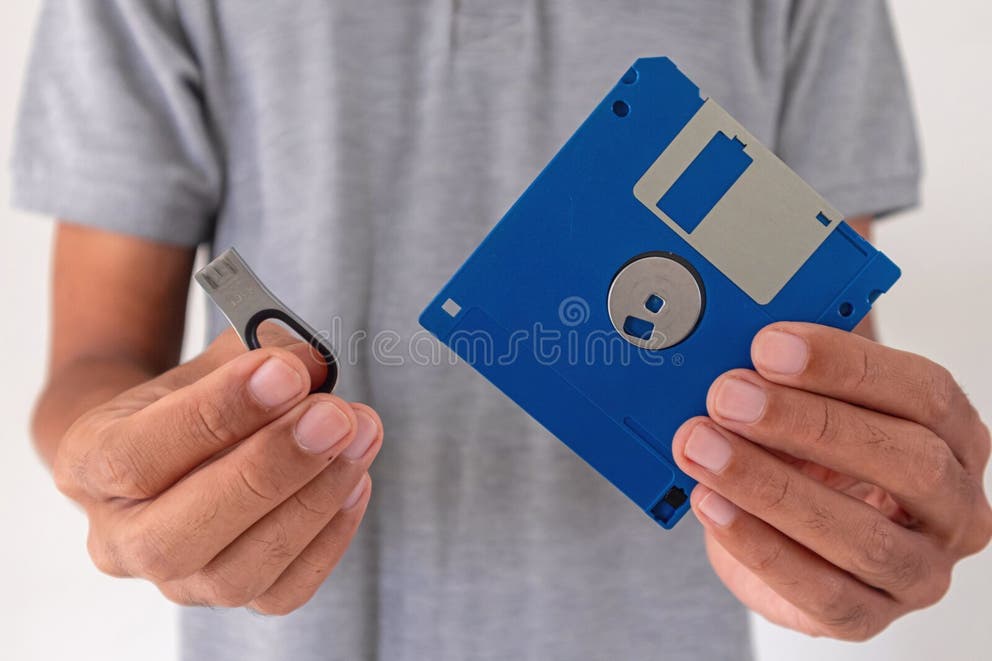 A Man Holding a USB Flash Drive in His Right Hand and a Floppy Disk in ...
