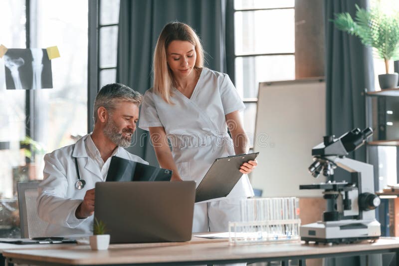 Man is Holding and Watching at X-ray. Two Clinic Workers are Indoors ...
