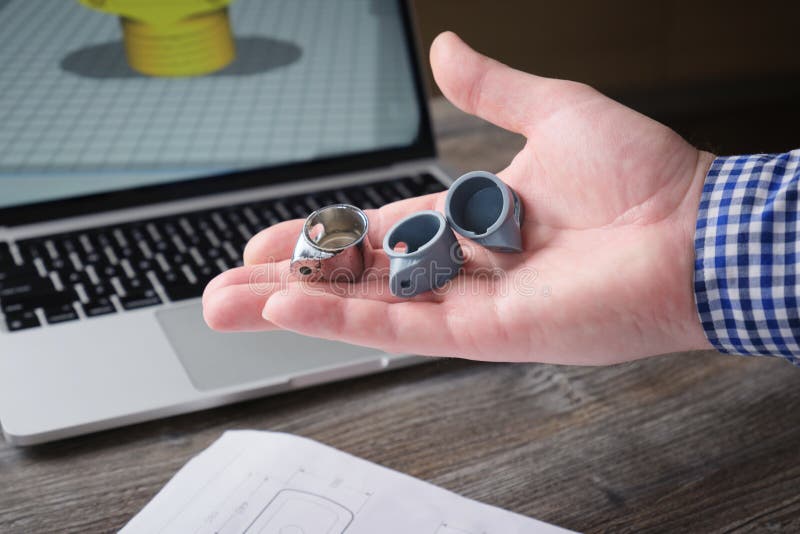 A Man Holds a 3D Printed Part in His Hand Against a Laptop with 3D ...