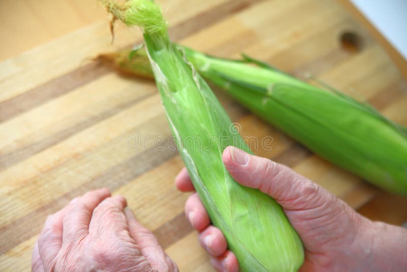 Man Holds Ear of Corn Over Cutting Board Stock Image - Image of space ...