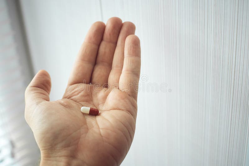 A Man Holds a Multi-colored Tablet in His Palm. the Cure for the Common ...