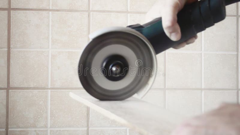 A Man Holds a Piece of Ceramic Tile with One Hand and Cuts the Tile ...
