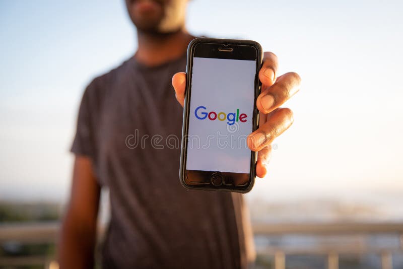 A Man Holds a Smartphone with the Google Logo on the Screen. Google is ...
