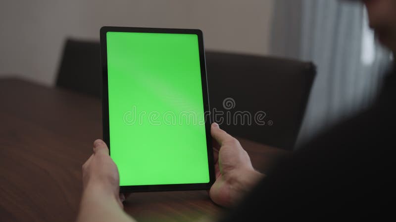 Man at Home Using Tablet Pc with Green Screen while Sitting at the ... Man at Home Using Tablet Pc with Green Screen while Sitting at the ...