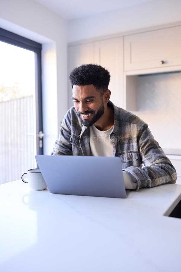 Man at Home Working on Laptop on Counter in Kitchen Stock Photo - Image ...