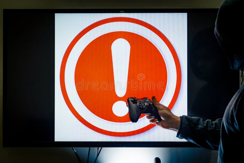 Man in Hood Holding Controller in Front of Screen Showing an Alert Red ...