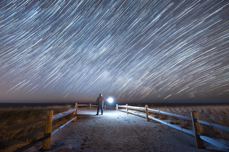Man Illuminating a Beach Path Under Star Trails. Stock Photo - Image of ...