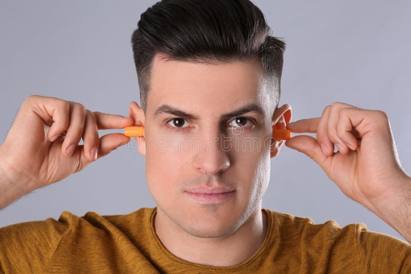Man Inserting Foam Ear Plugs on Grey Background Stock Image - Image of ...