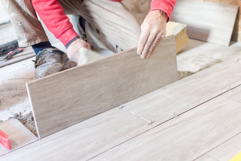 Man Installing Rectangular Shaped Floor Tiles in Kitchen. Applying Adhesive before Installation ...