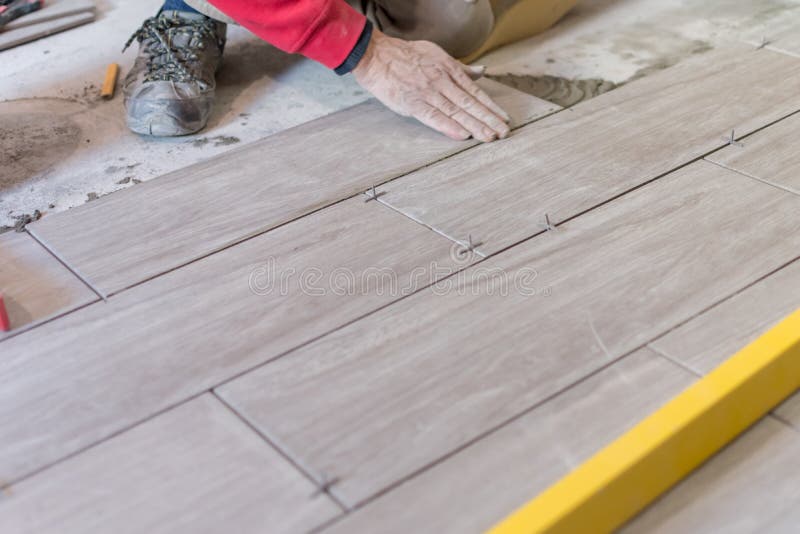 Man Installing Rectangular Shaped Floor Tiles in Kitchen. Applying Adhesive before Installation ...