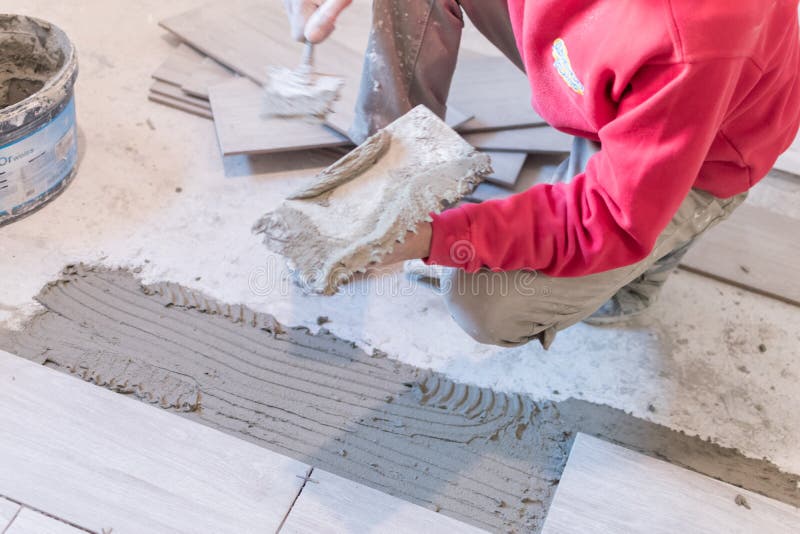Man Installing Rectangular Shaped Floor Tiles in Kitchen. Applying ...
