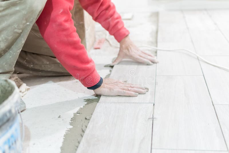 Man Installing Rectangular Shaped Floor Tiles in Kitchen. Applying Adhesive before Installation ...