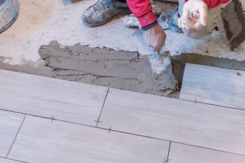 Man Installing Rectangular Shaped Floor Tiles in Kitchen. Applying Adhesive before Installation ...