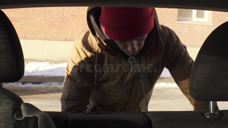 Man in a Jacket is Opening the Trunk of a Car and Putting a Backpack ...