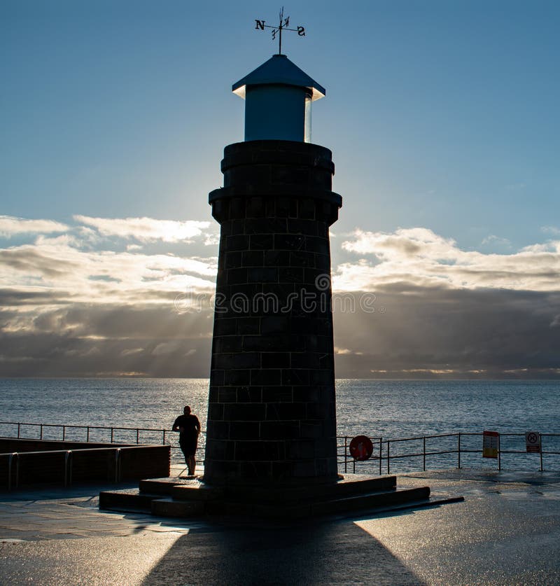A Man Jogs Around a Lighthouse with Him and the Lighthouse is Harp ...