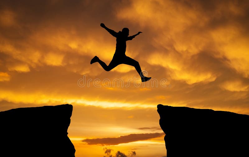 Man Jumping Over Rocks with Gap on Sunset Fiery Background. Stock Image ...