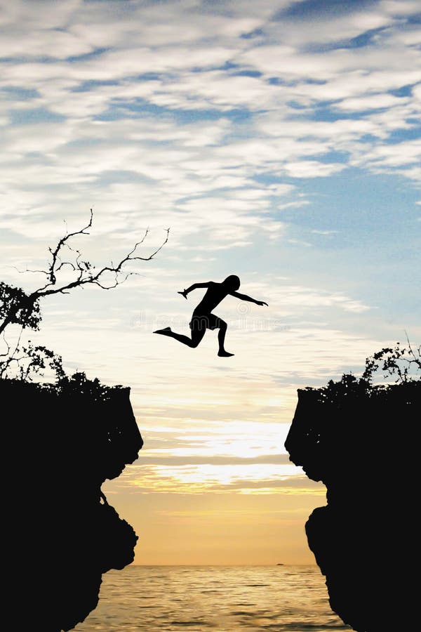 Man Jumping between Two Rocky Mountains at Sunset Stock Photo - Image ...
