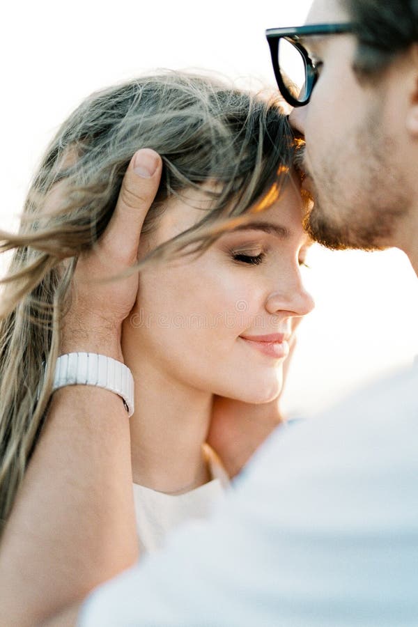 Man Kisses Woman On The Forehead Holding Her Head In His Hands