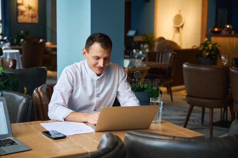 Man in Kitchen Uniform Works with Documents in Restaurant Hall Stock ...