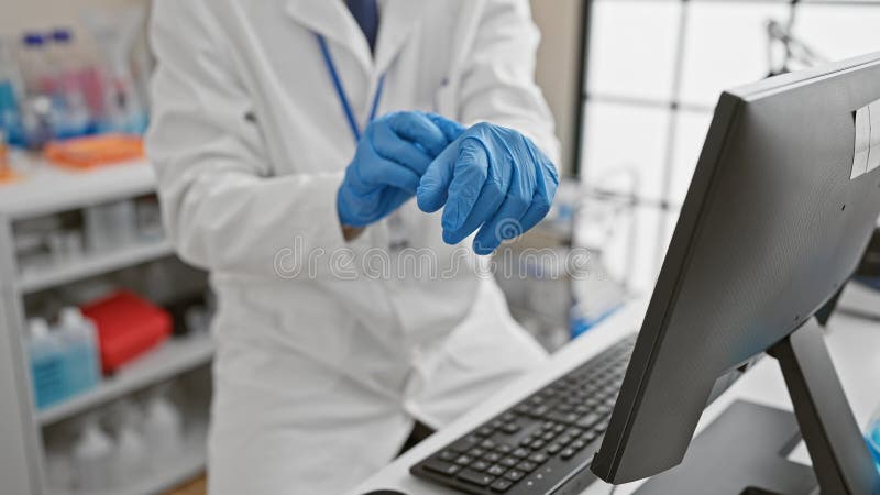 A Man in a Lab Coat with Gloves Uses a Computer in a Modern Laboratory ...